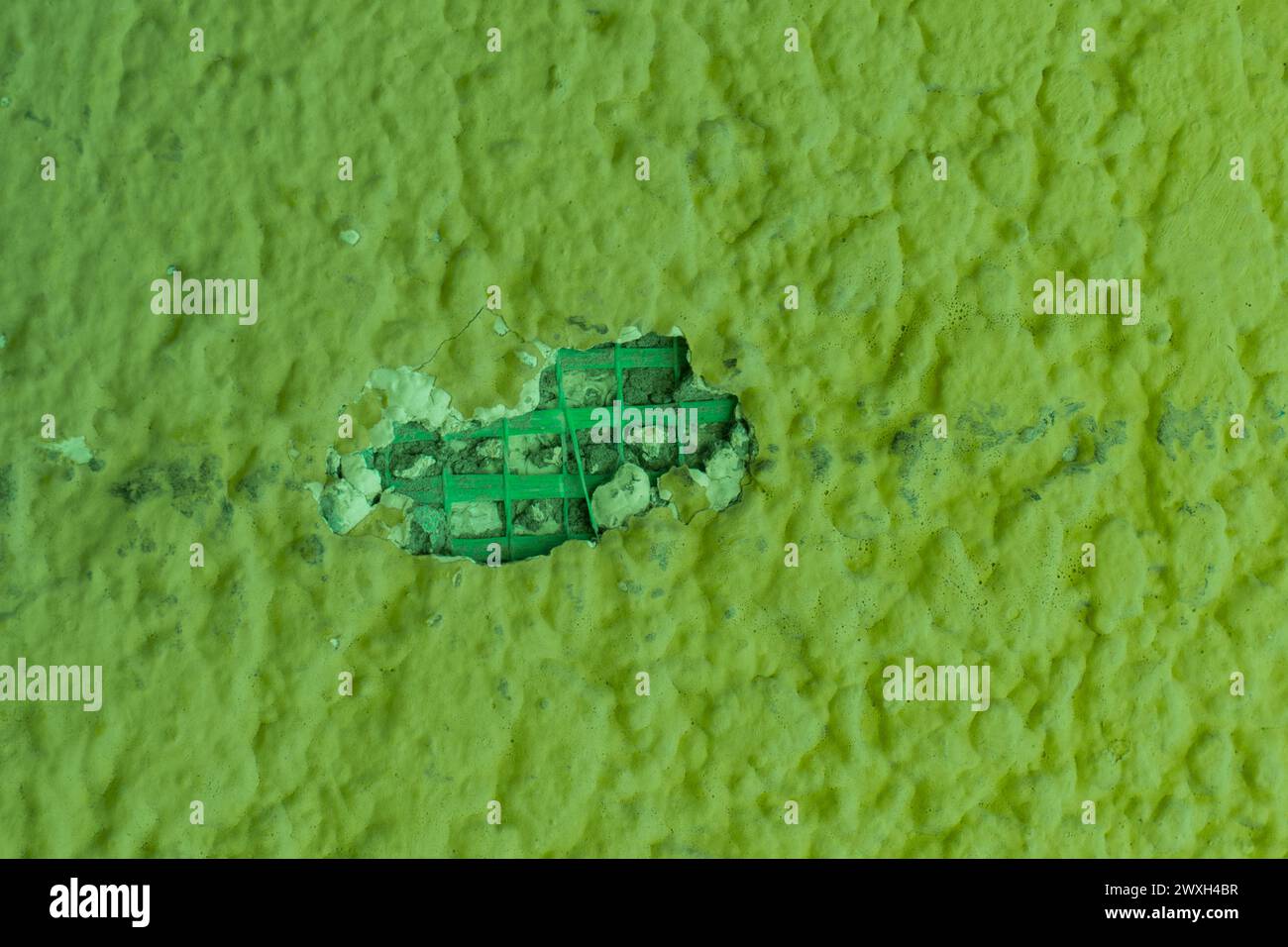 Broken wall green plaster damaged surface hole close-up building ...