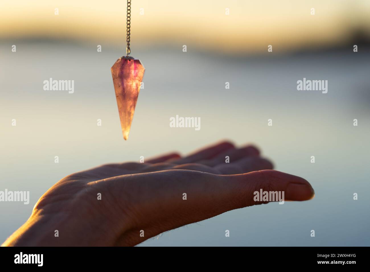 Pendulum over a hand seen up close in nature Stock Photo - Alamy