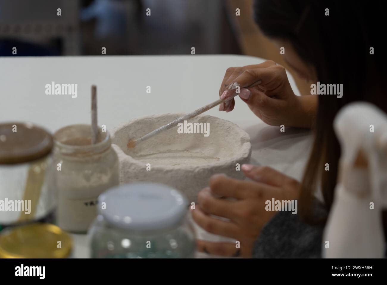 Woman glazing a piece of pottery in a pottery workshop Stock Photo - Alamy