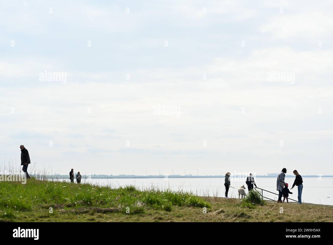 31 March 2024, Ditzum: Many passers-by enjoy the sunny weather on ...