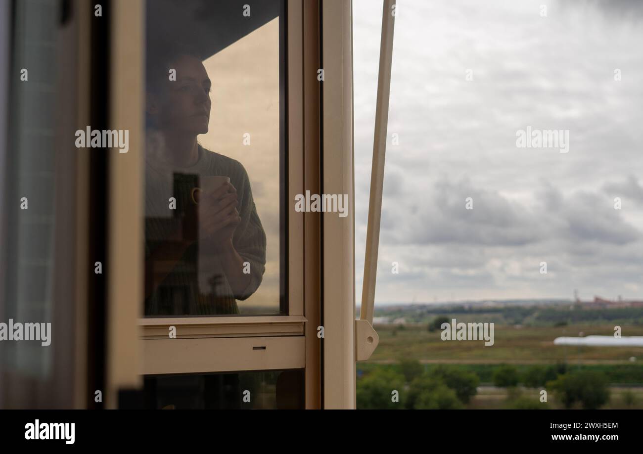 Woman looking through a window Stock Photo - Alamy