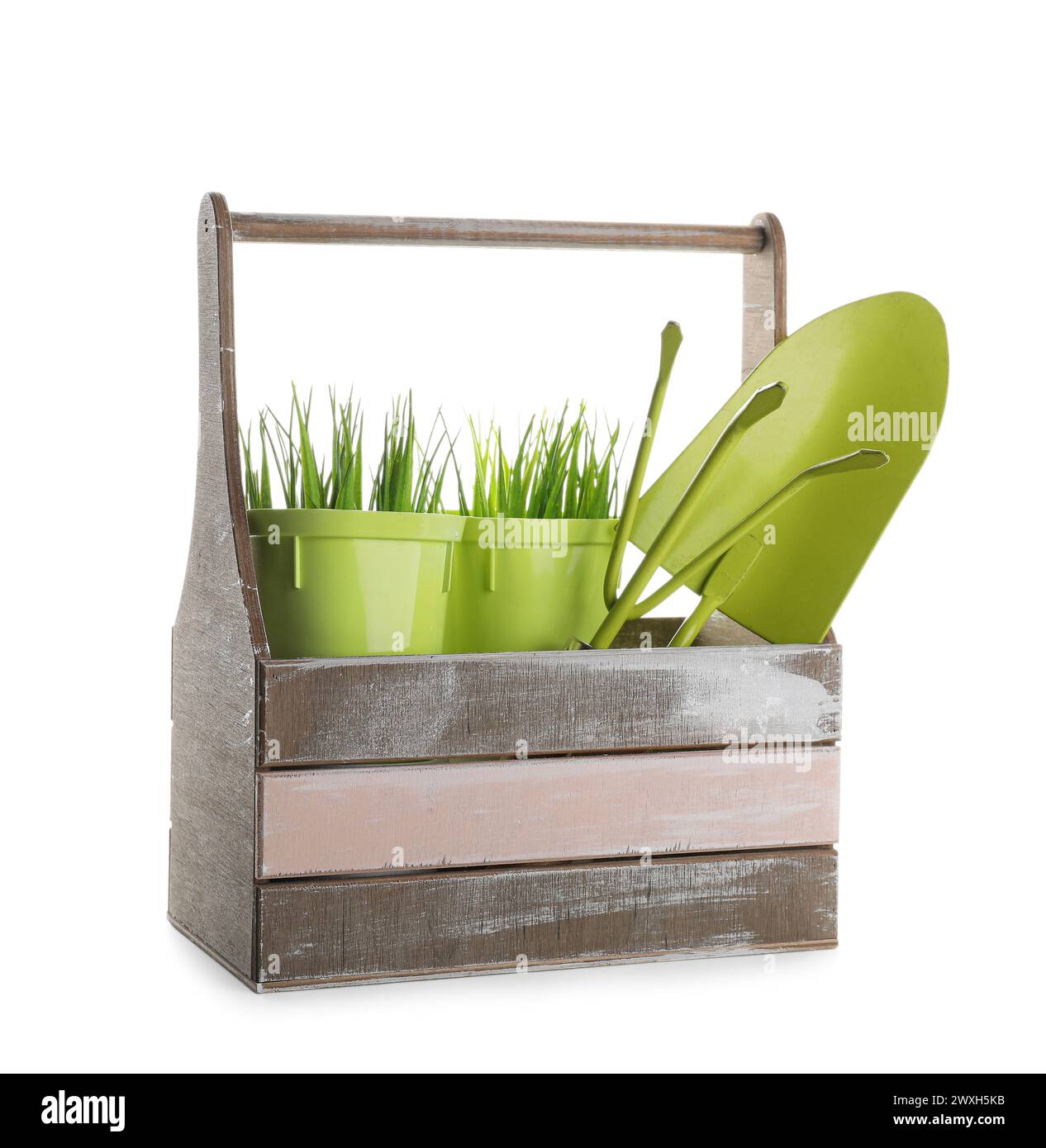 Composition with grass and gardening tools in basket on white ...