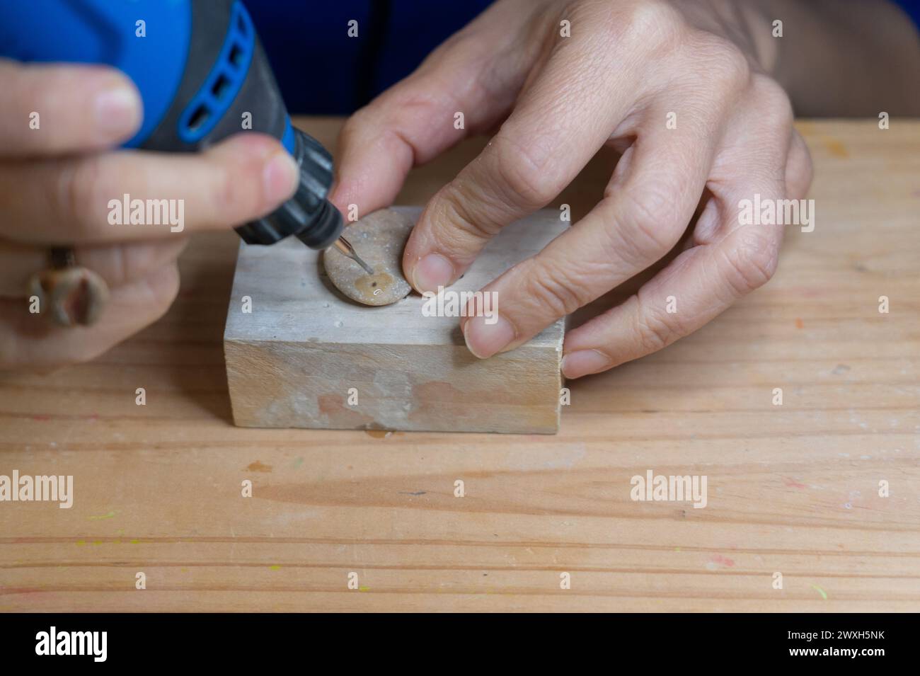 Person making a hole in a stone with a rotary tool Stock Photo - Alamy