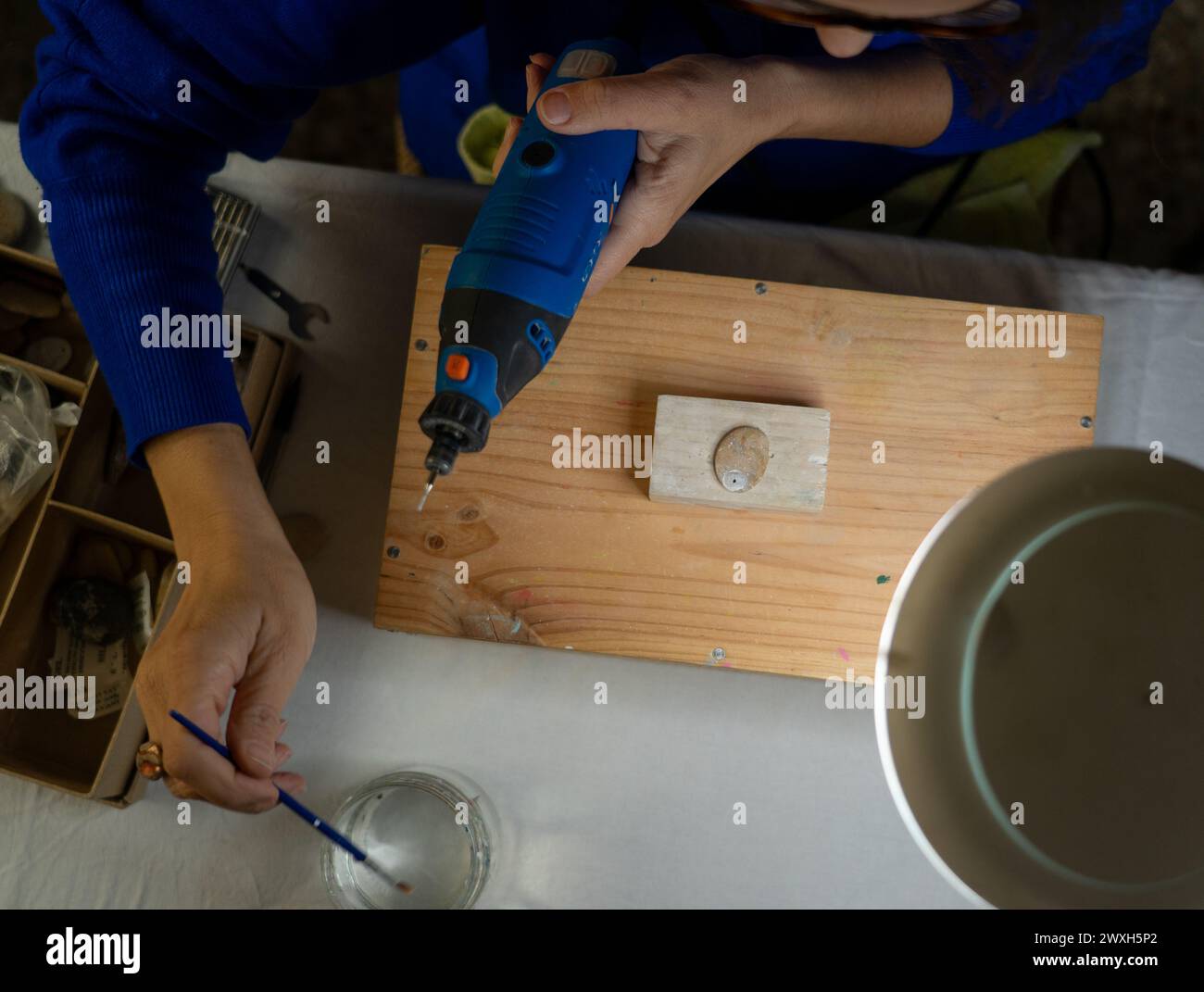 Artisan woman carving a stone with a rotary tool in her workshop seen ...