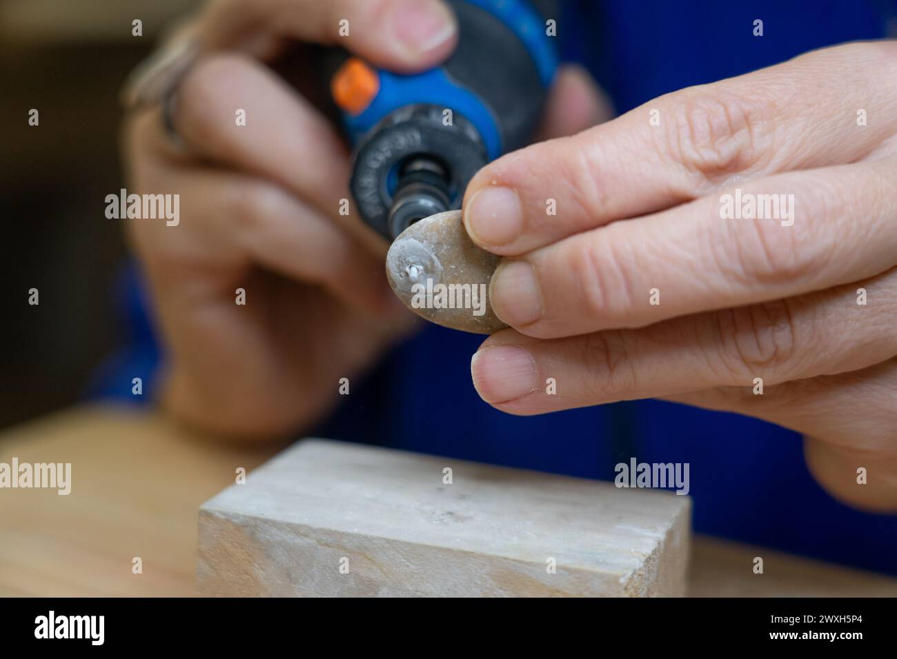 Artisan woman making a hole in a stone with a rotary tool seen up close ...