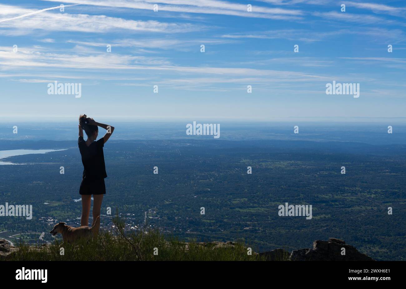 Woman making a ponytail on top of a mountain looking up at the views ...