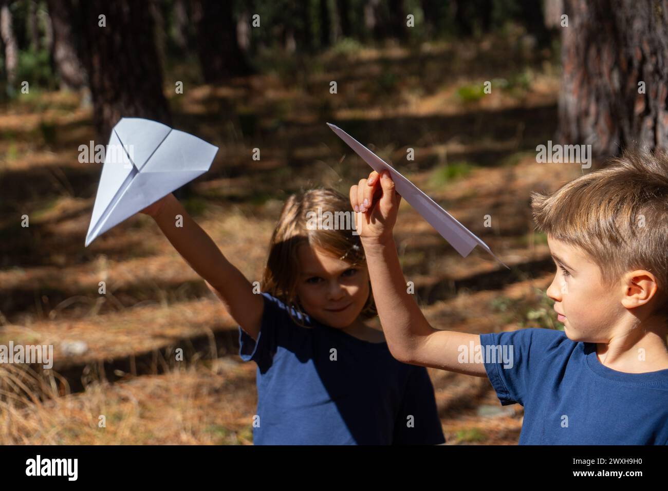 Two children in the woods playing with paper airplanes Stock Photo - Alamy
