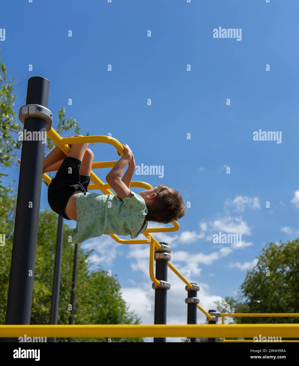 Child climbing over the top of a playground structure Stock Photo - Alamy