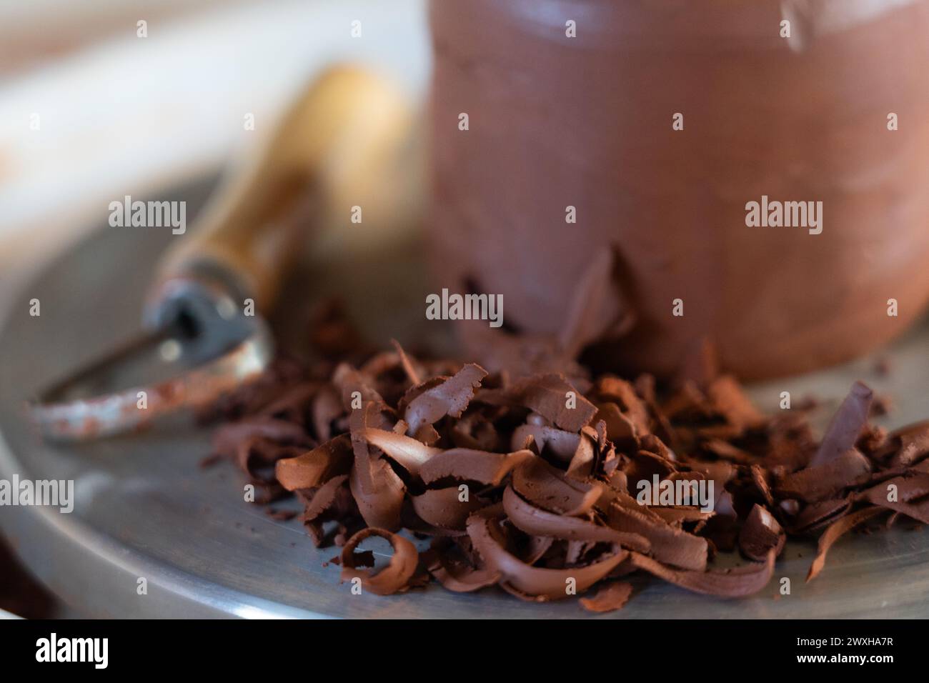 Clay piece seen up close with pottery tools and clay shavings on top of ...