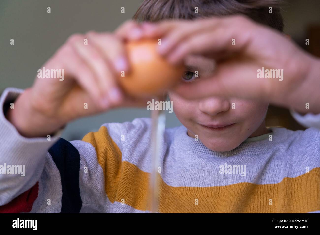 Concentrated child opening an egg to cook pastry Stock Photo - Alamy