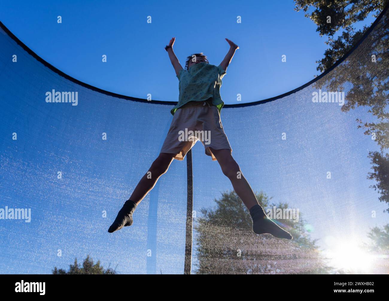 Child jumping on a trampoline with feet and hands stretched out Stock ...
