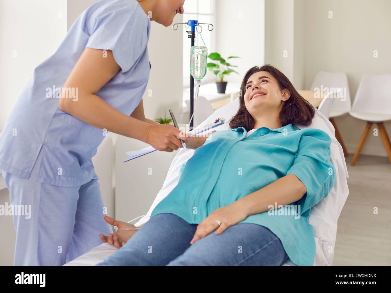 Nurse help pregnant woman in receiving IV drip infusion and vitamin ...