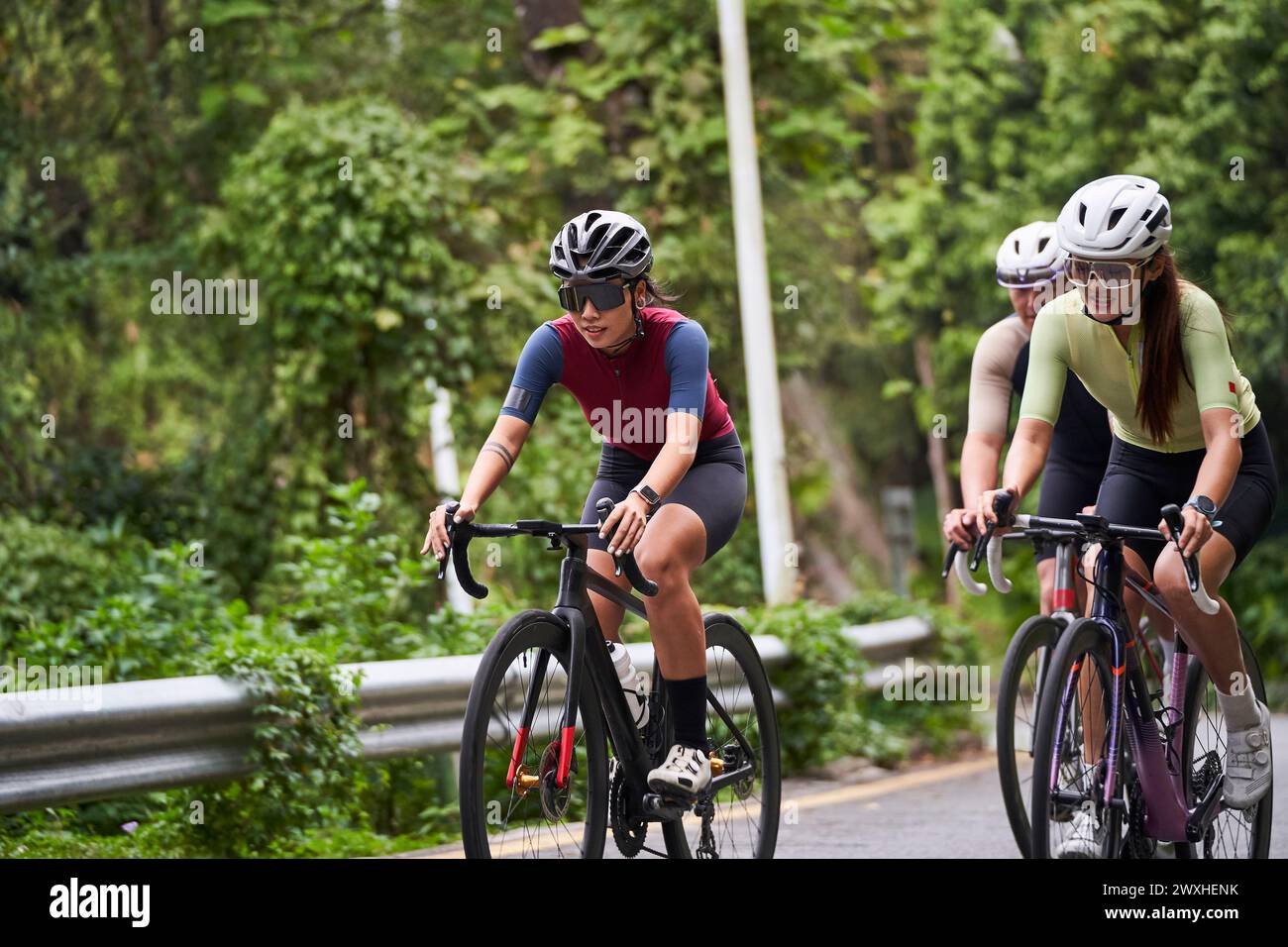 group of three young asian adult cyclists riding bike outdoors on rural ...