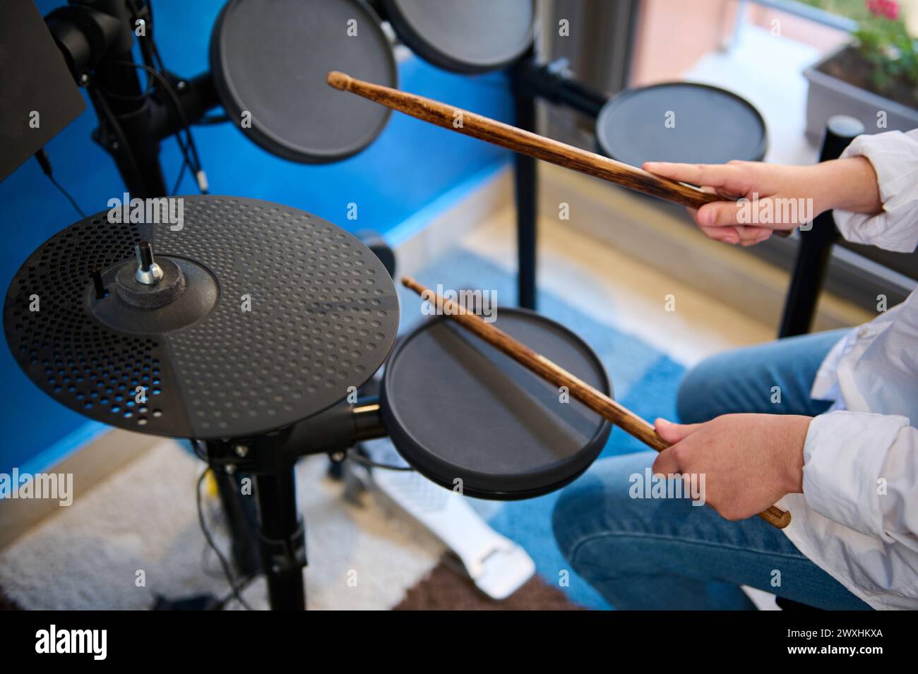 Close up view from above of teenage drummer hands. Teen boy playing drums in music studio. Top ...