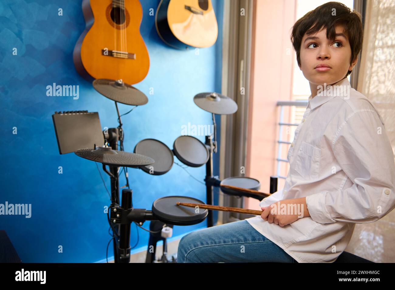 Confident Caucasian teen boy drummer musician sitting at drum set in a ...