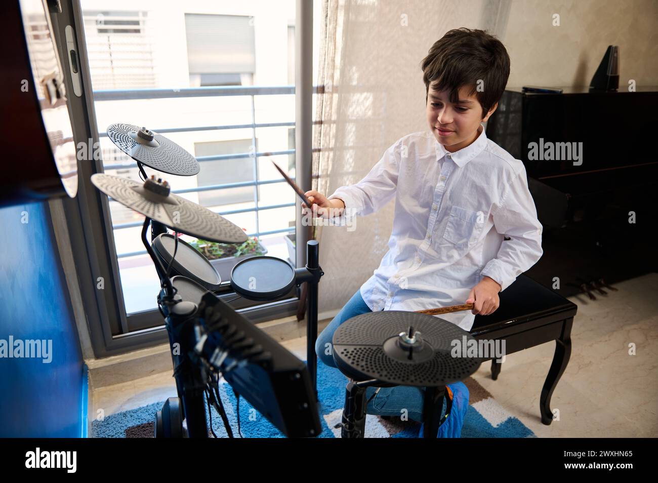 Handsome happy teenager boy playing drums at home music studio, holding ...