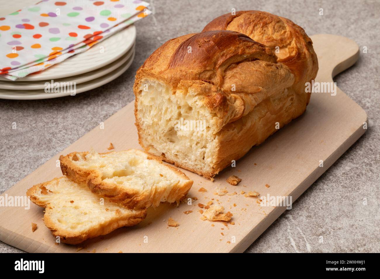 Fresh baked loaf of croissant bread and slices on a cutting board close ...