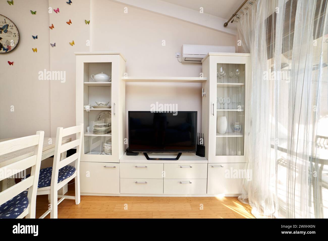 TV stands on a cabinet in the living room next to a table with chairs ...
