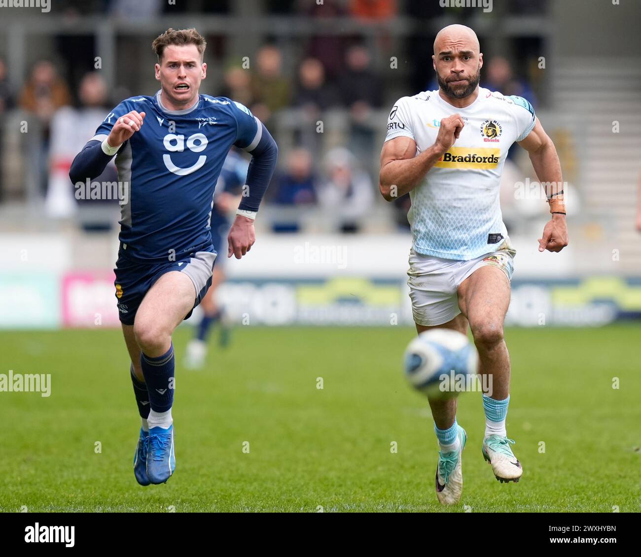 Tom Roebuck of Sale Sharks and Olly Woodburn of Exeter Chiefs chase a ...
