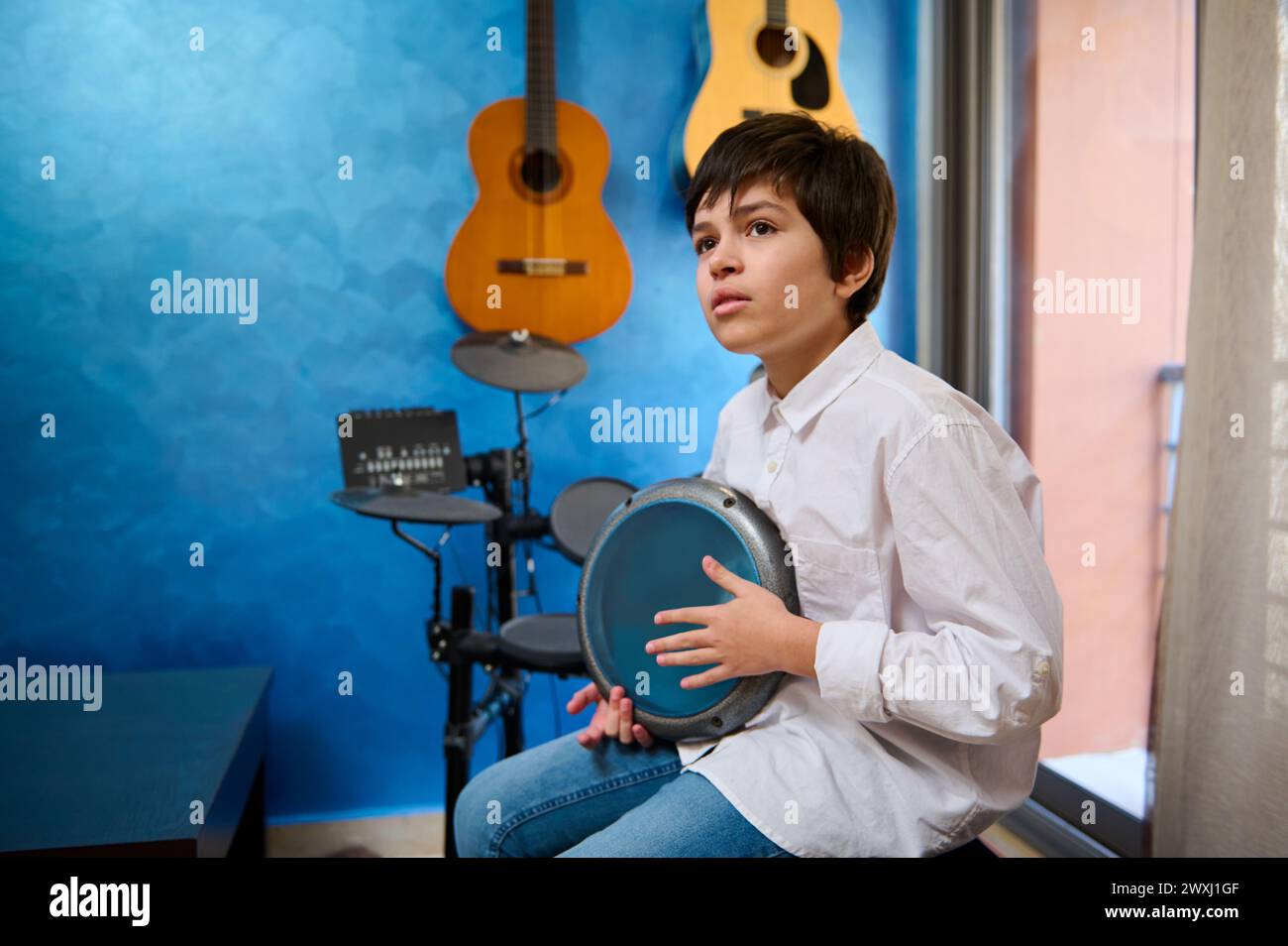 Caucasian child boy musician playing drums, creating rhythm of music ...