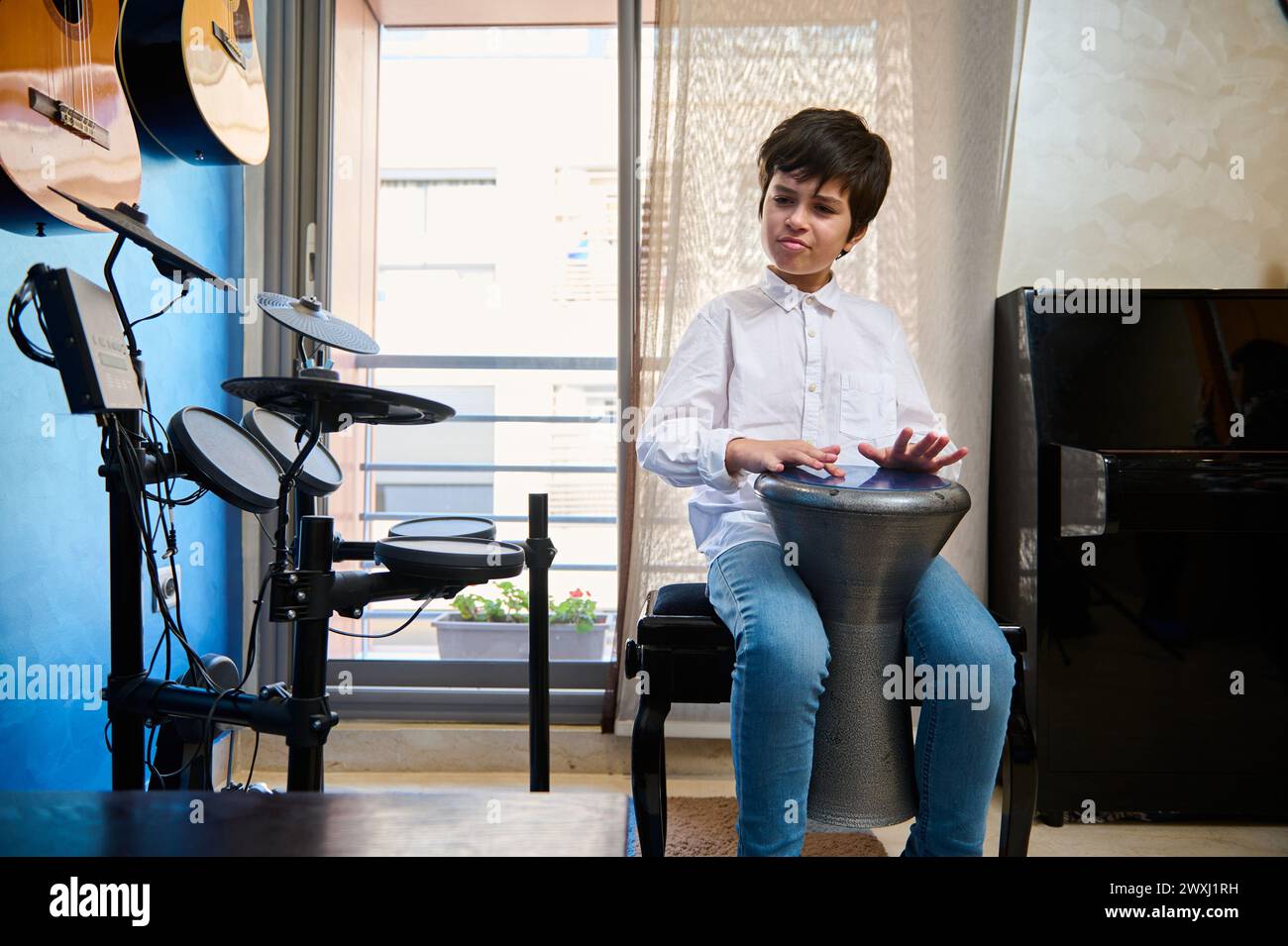 Caucasian handsome teenager, boy musician drummer banging drums tam tam ...