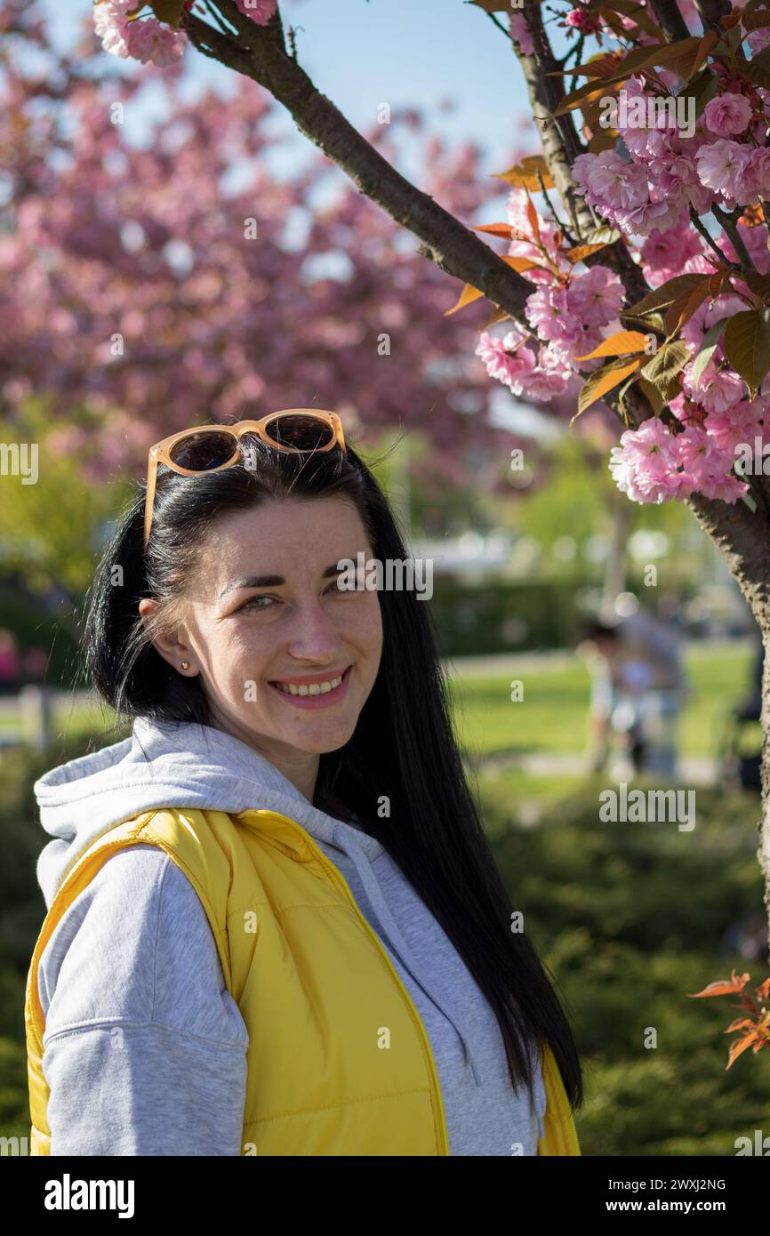 A happy mother and child are walking under the branches of a cherry ...