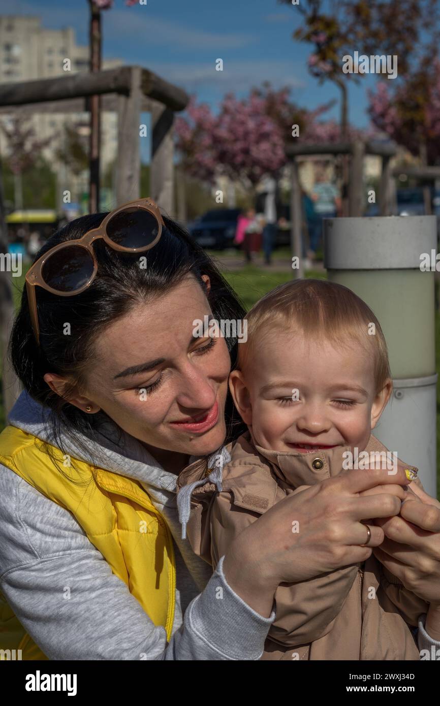 A happy mother and child are walking under the branches of a cherry ...