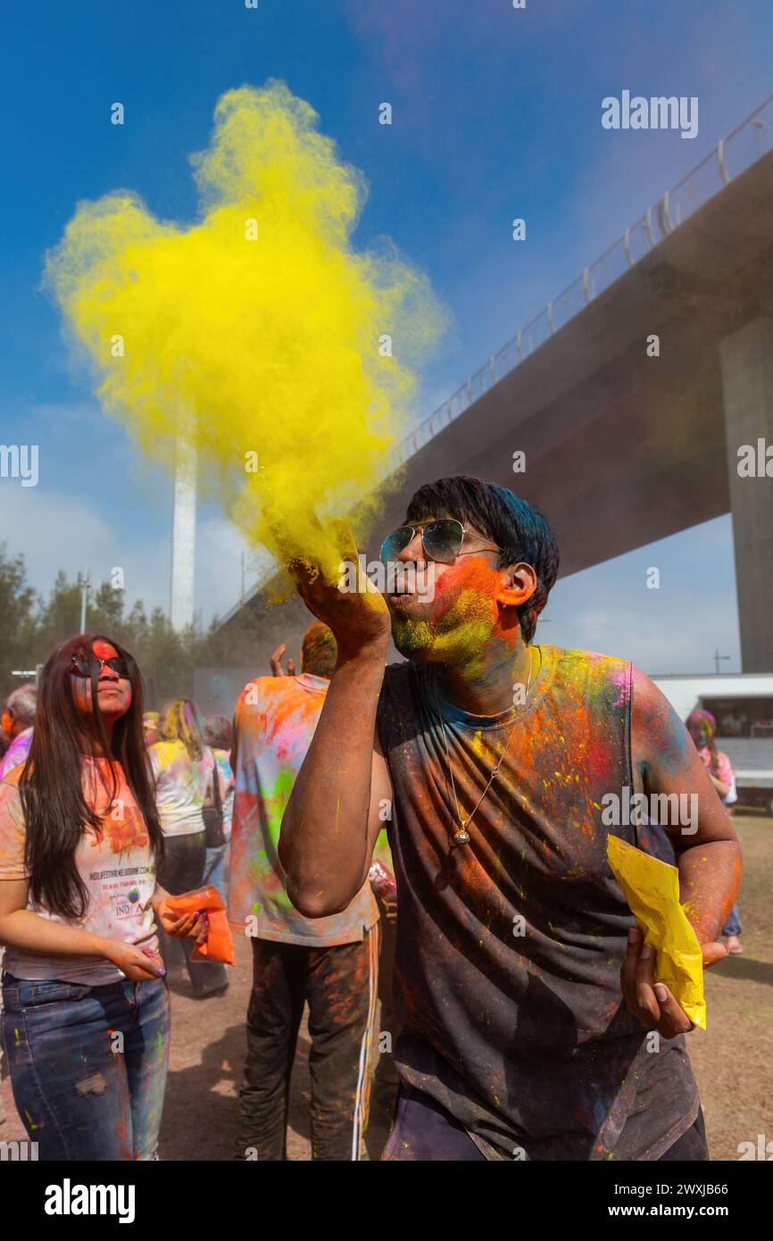 A man blows colour powder from his hand into the air during an event to ...