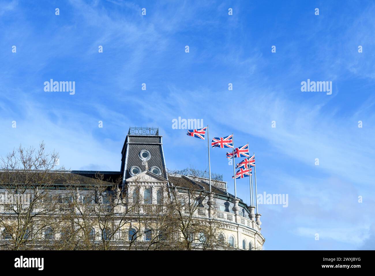 Union Jack UK flags flying against a blue sky above the Grand Buildings ...