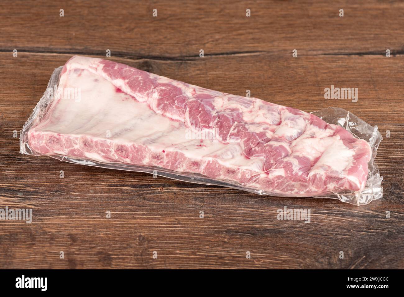 Vacuum-packed raw pork ribs on a tree background. Home cooking Stock ...