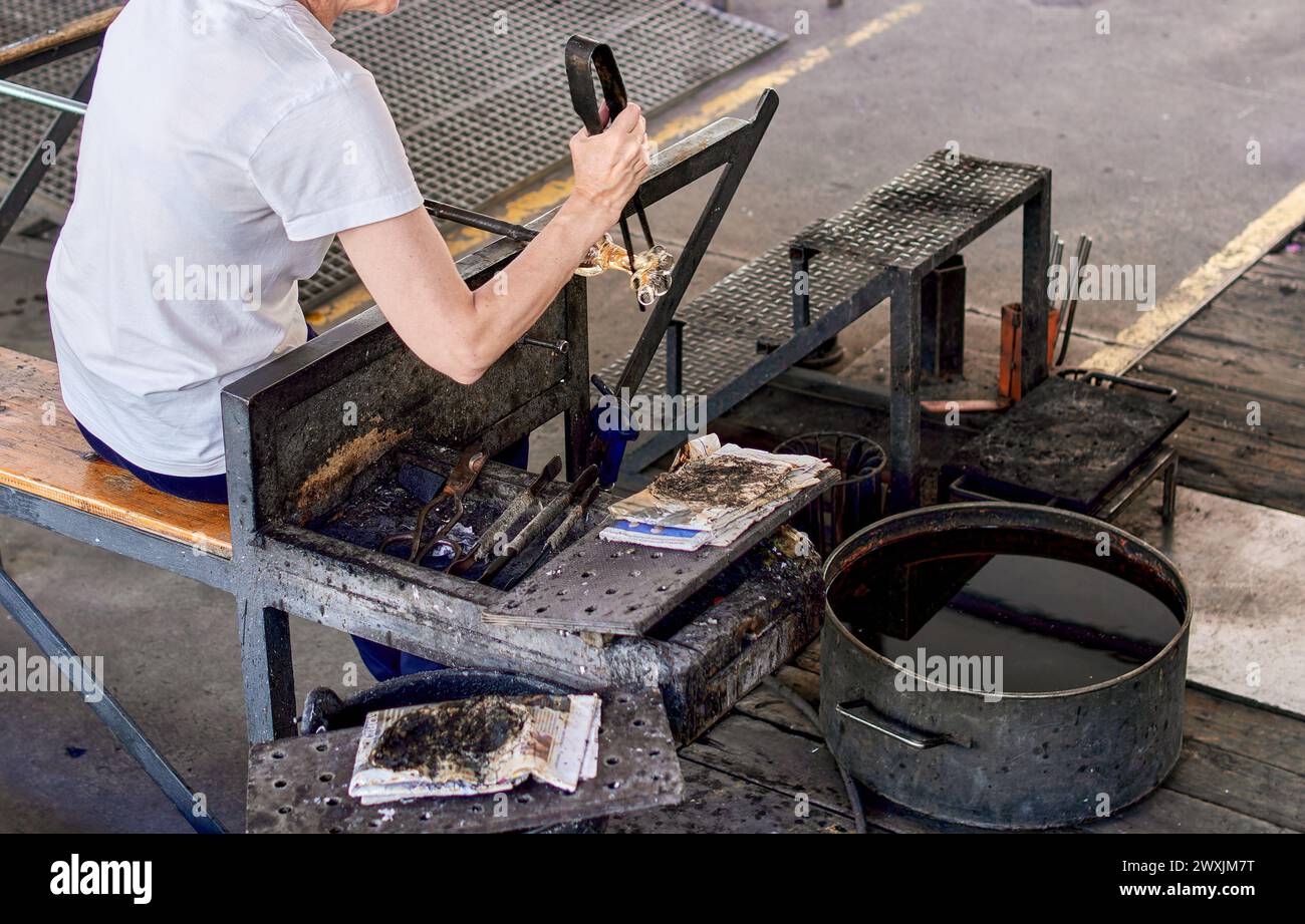 Craftsman working diligently at cluttered workbench with tools and ...