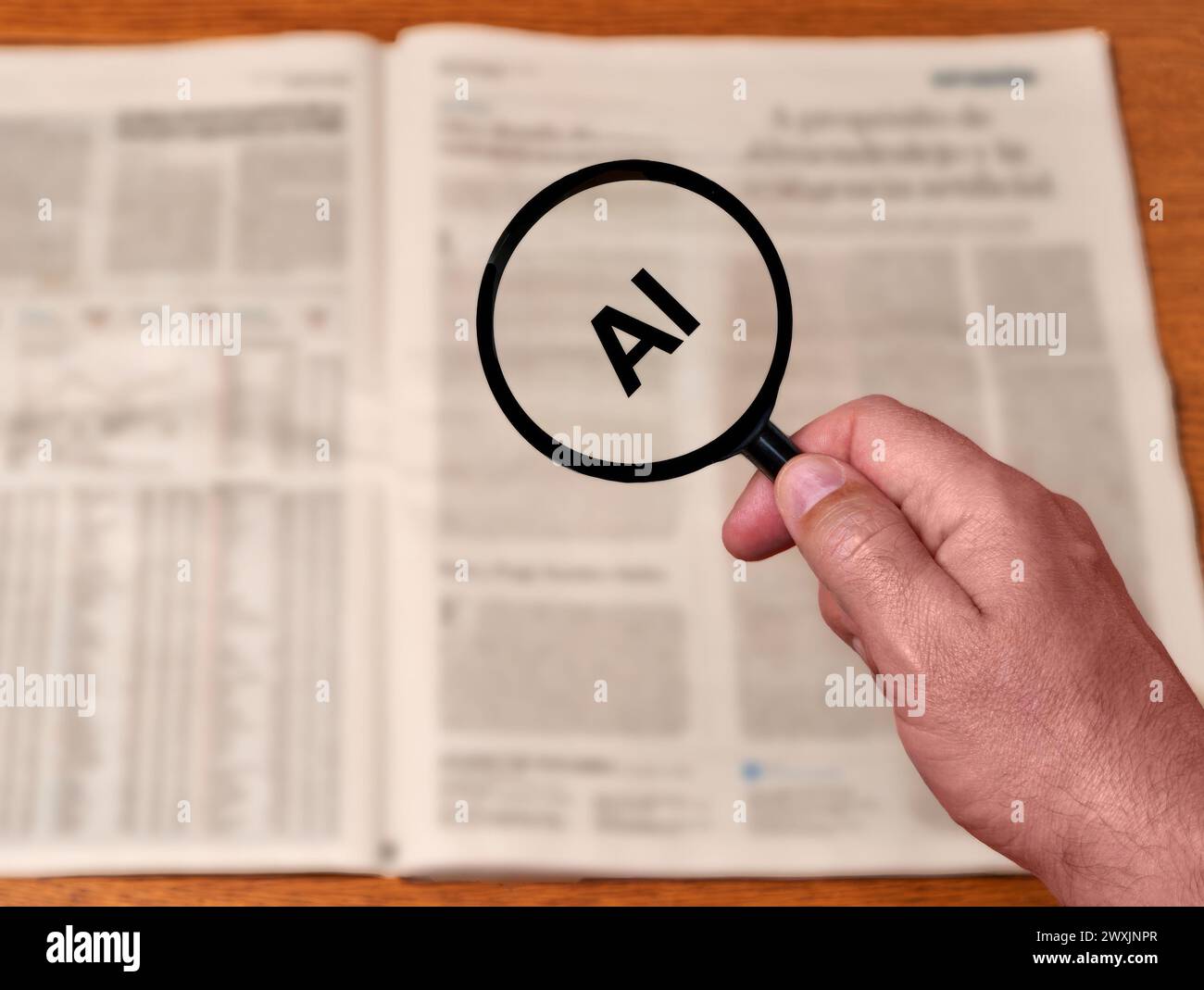 Hand holding magnifying glass over newspaper revealing Hand holding magnifying glass over newspaper revealing