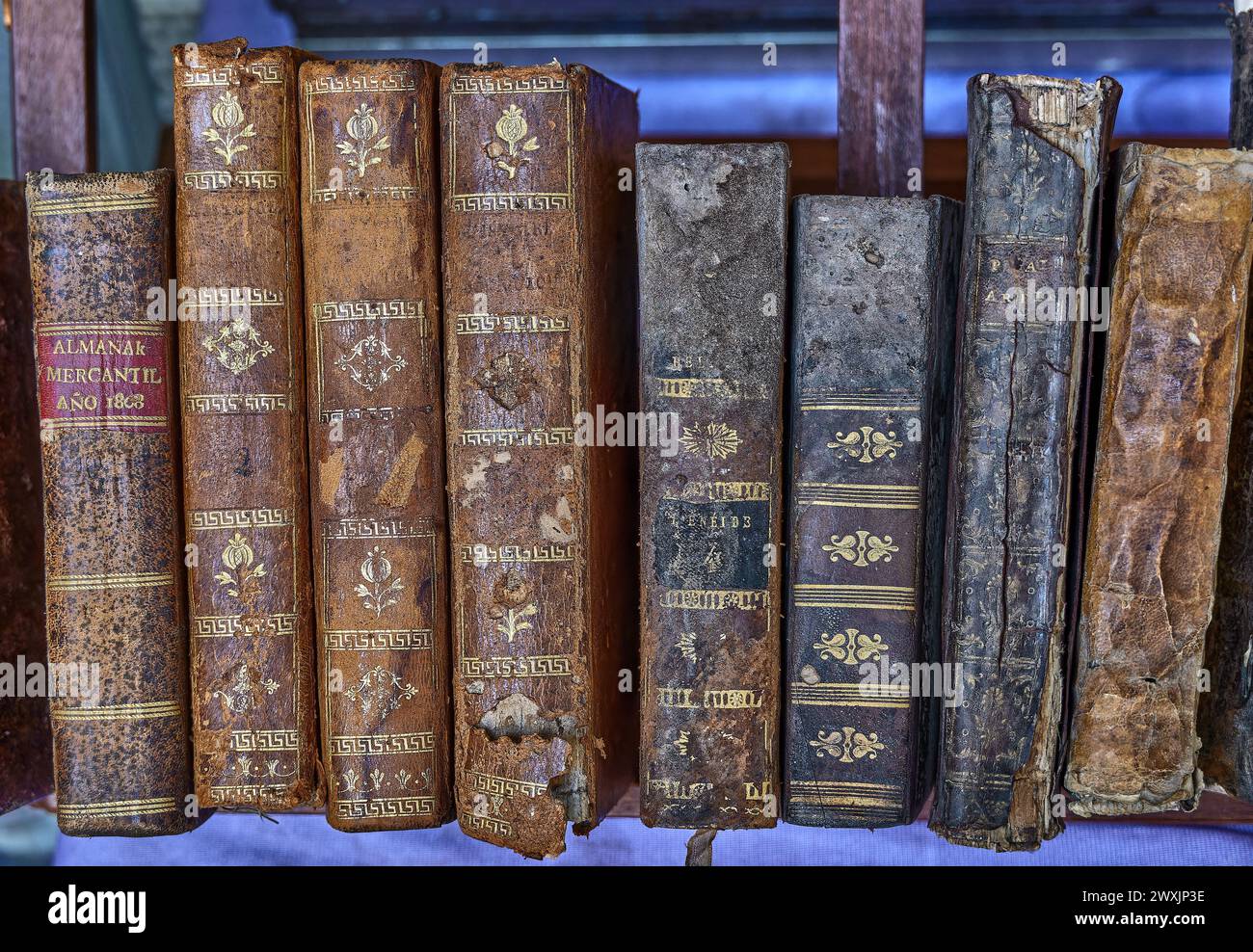 A collection of old, worn books with intricate designs on the spines ...