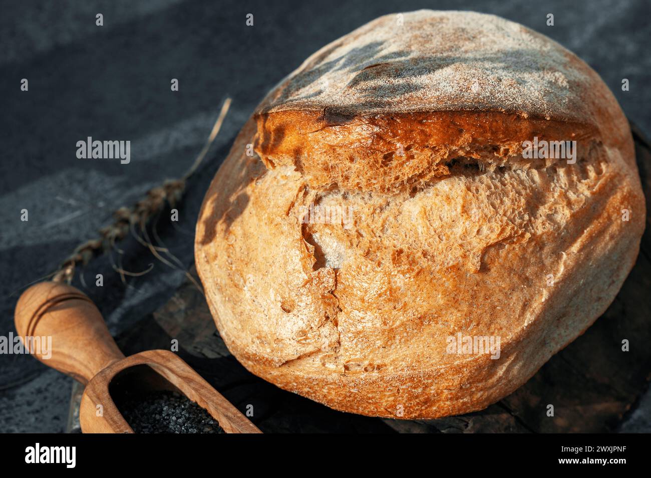 Round white bread. Close-up of white bread with homemade black salt in ...