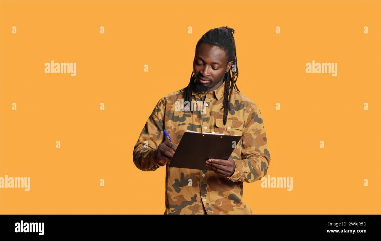 African american guy looks at checklist on clipboard files, taking ...