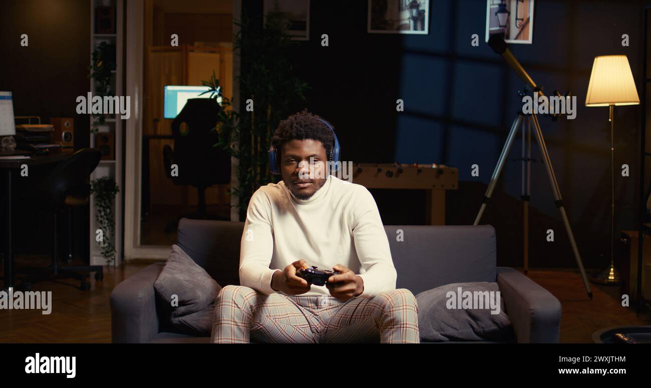 African american man playing shooter videogame in warm apartment ...