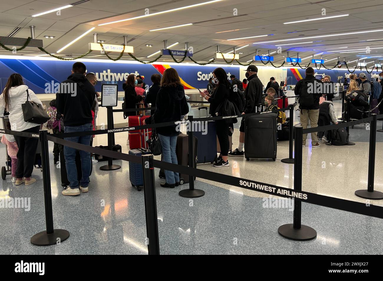Passengers wearing face masks wait in line at Southwest Airlines ...