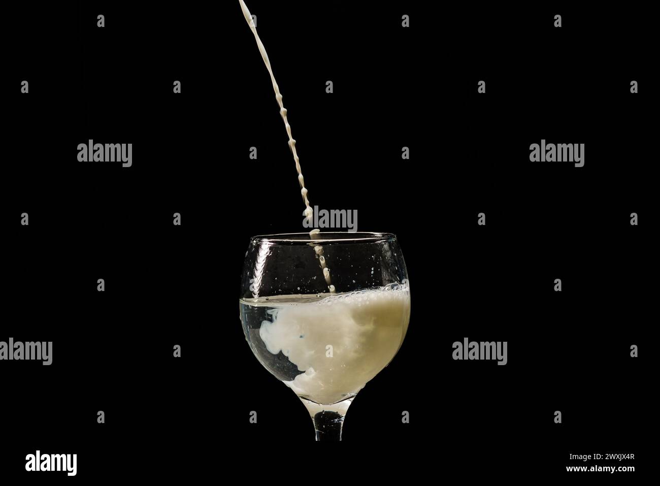 Milk falling into a glass cup. Isolated on black background Stock Photo ...