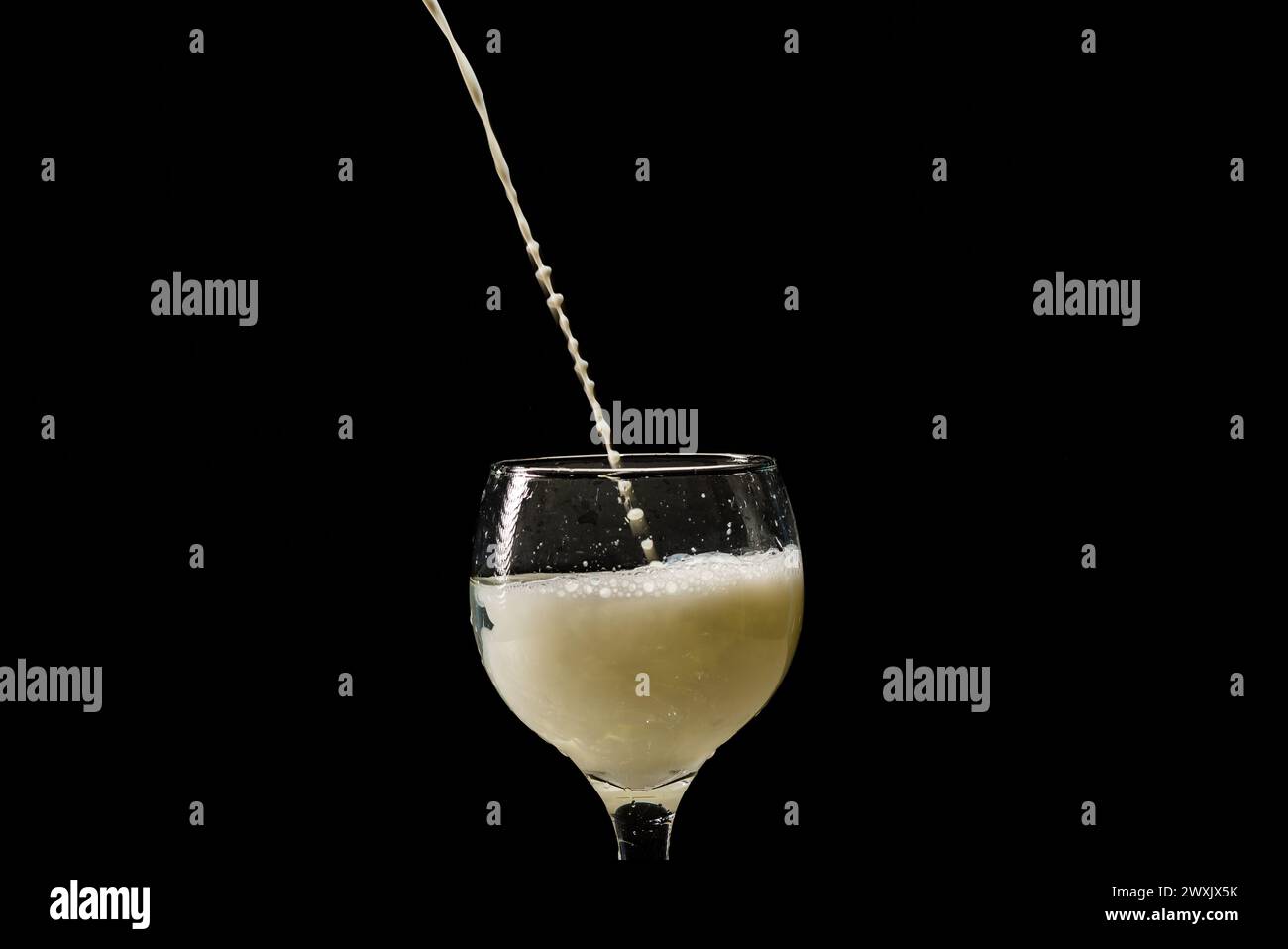 Milk falling into a glass cup. Isolated on black background Stock Photo ...