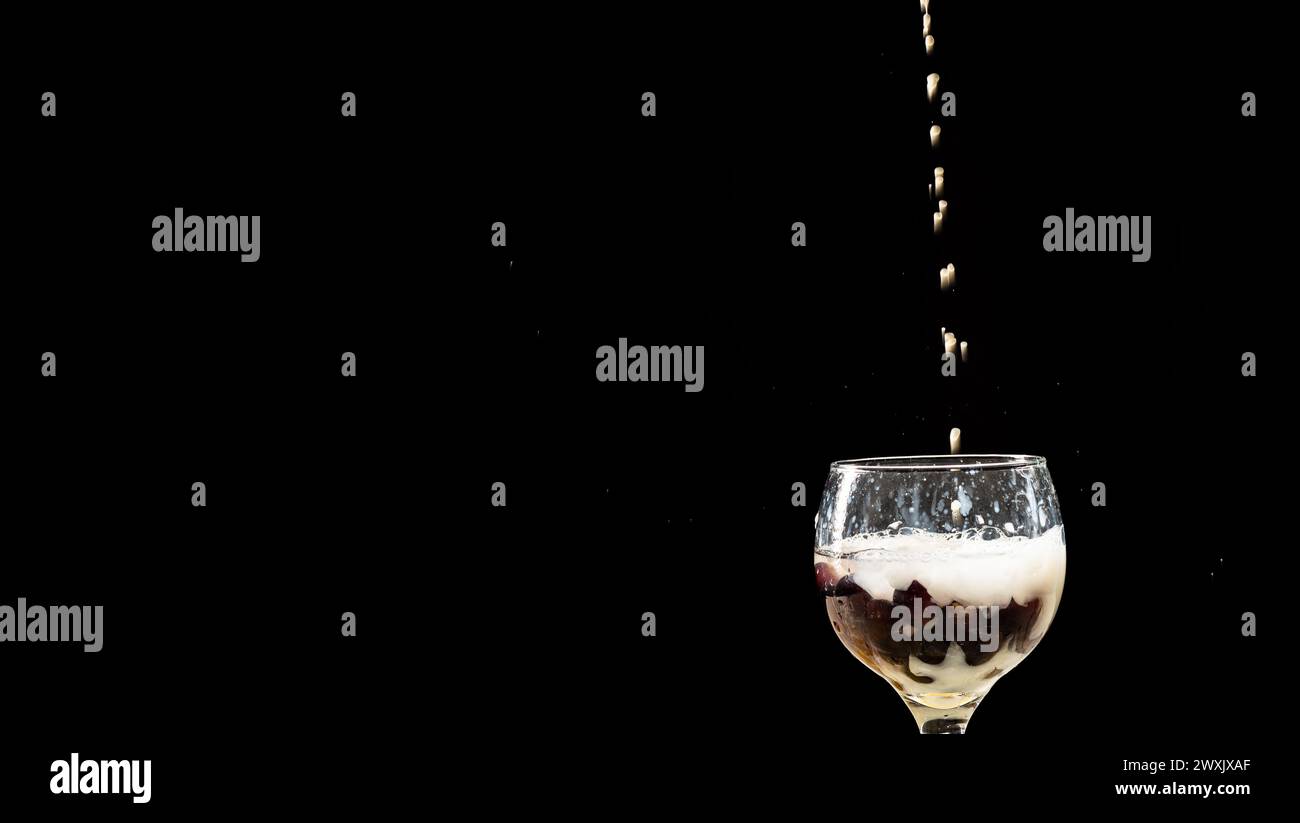 Drops of milk falling from above into glass wine glass with milk and ...