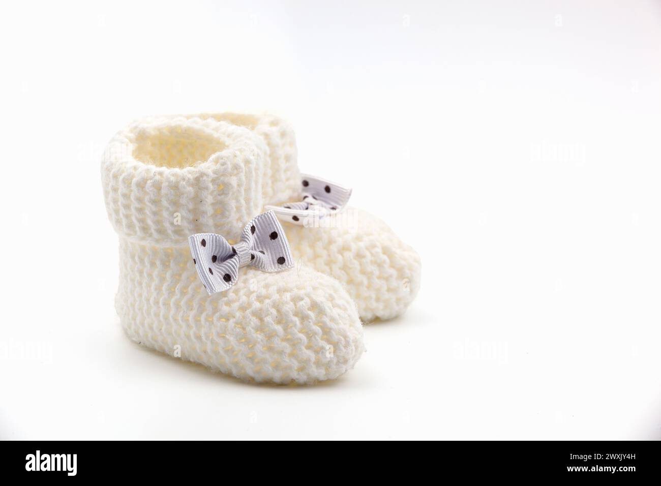 White crochet baby booties with black polka dot bows isolated on a ...