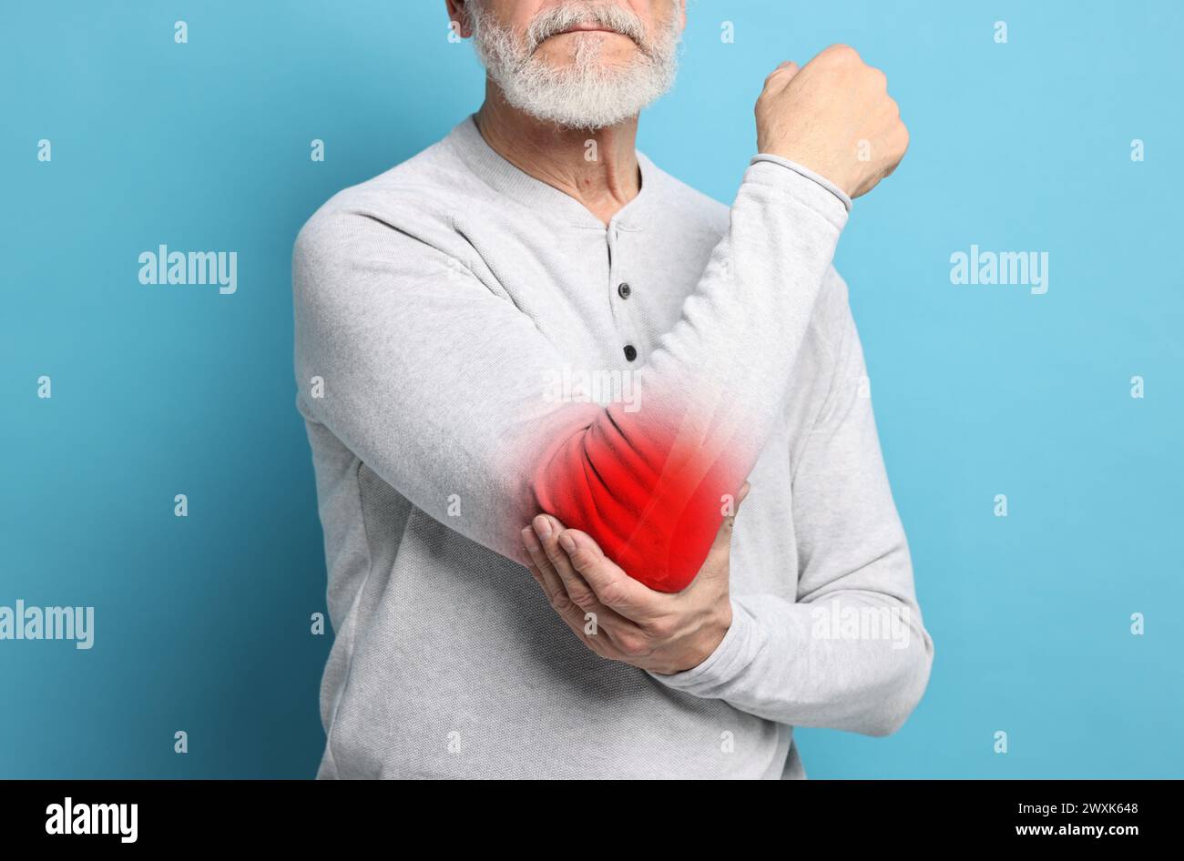 Arthritis symptoms. Man suffering from pain in his elbow on light blue ...