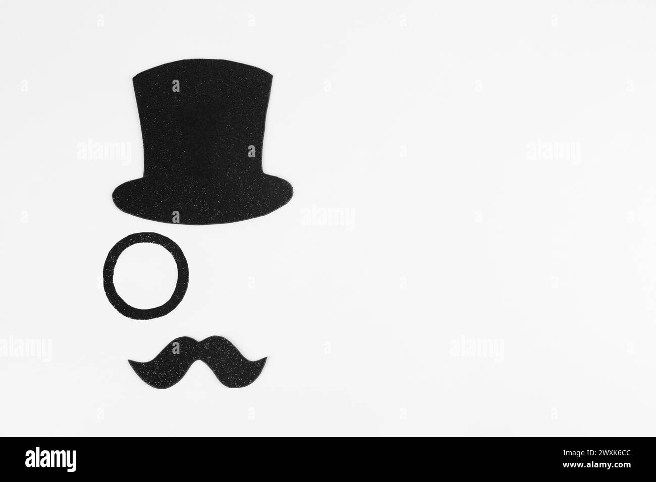 Fake mustache, hat and monocle on white background, top view. Space for ...