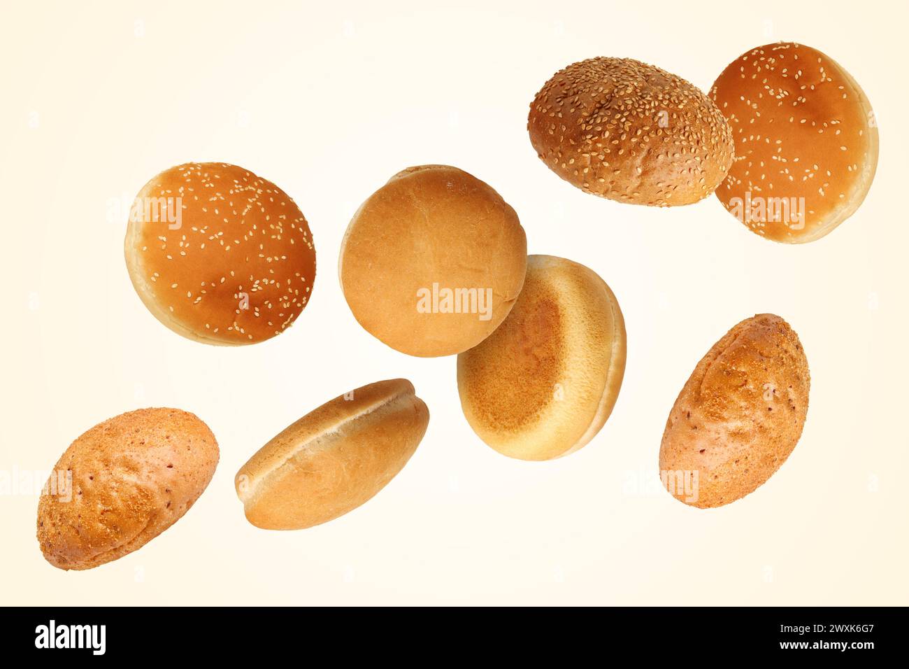 Fresh burger buns falling on beige background Stock Photo - Alamy