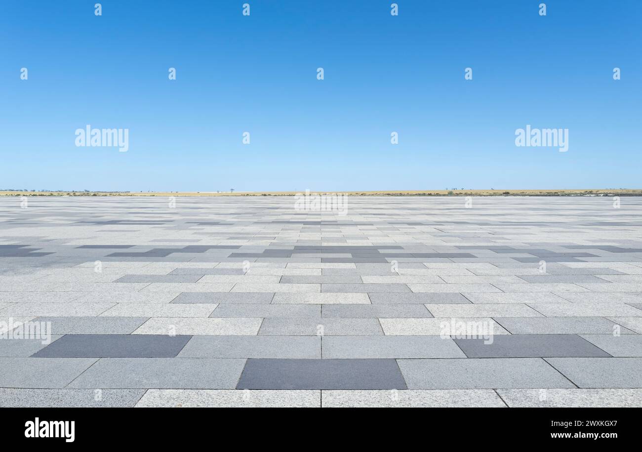 An empty concrete floor stretches out with a clear blue sky in the ...