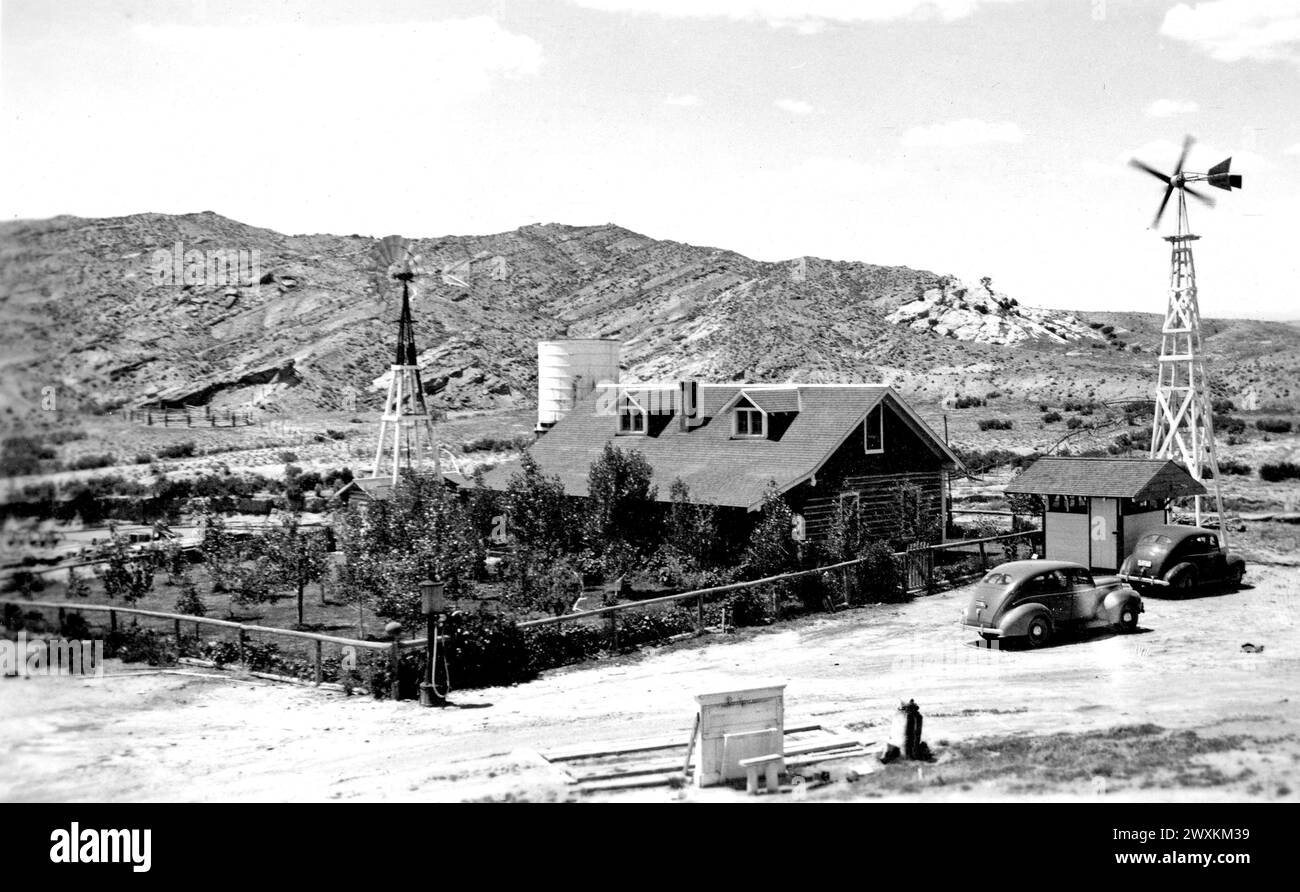 House on a ranch in central Wyoming, with parked cars and windmill ca ...