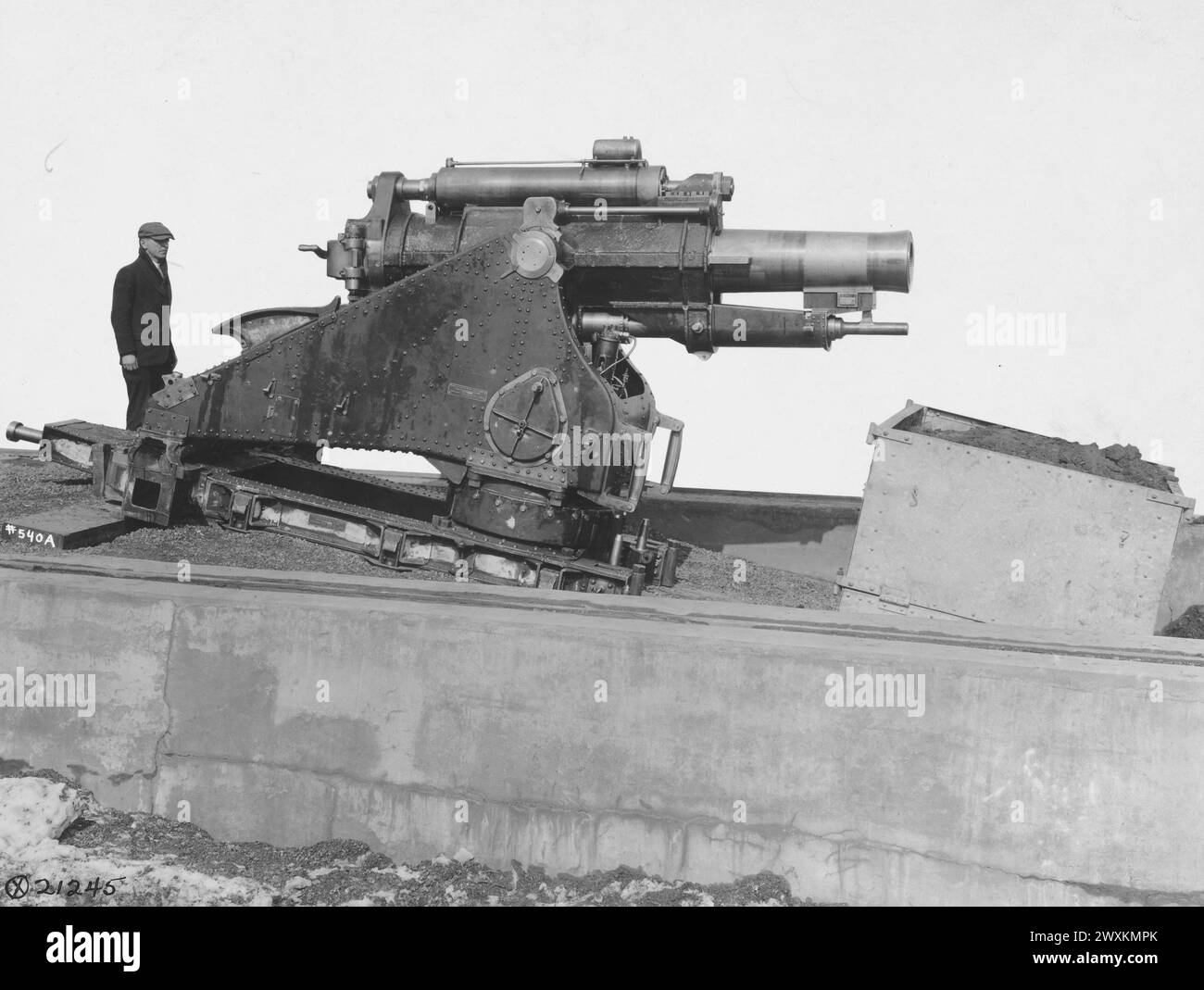 Man standing behind a 9.2" British Howitzer and mount on the proving ...