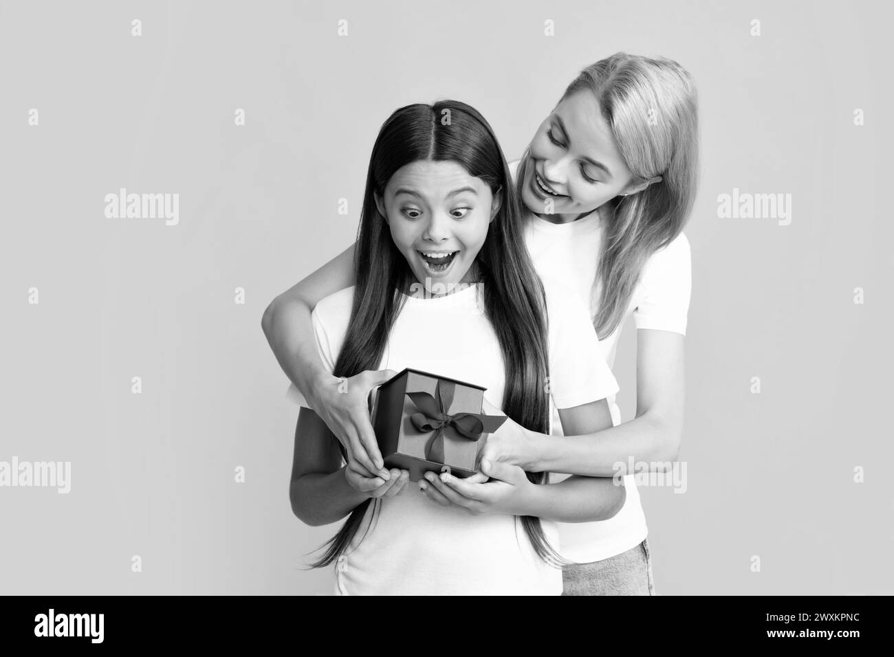 Young teen girl giving gift box to her mother on color background. Happy family. Mother and ...