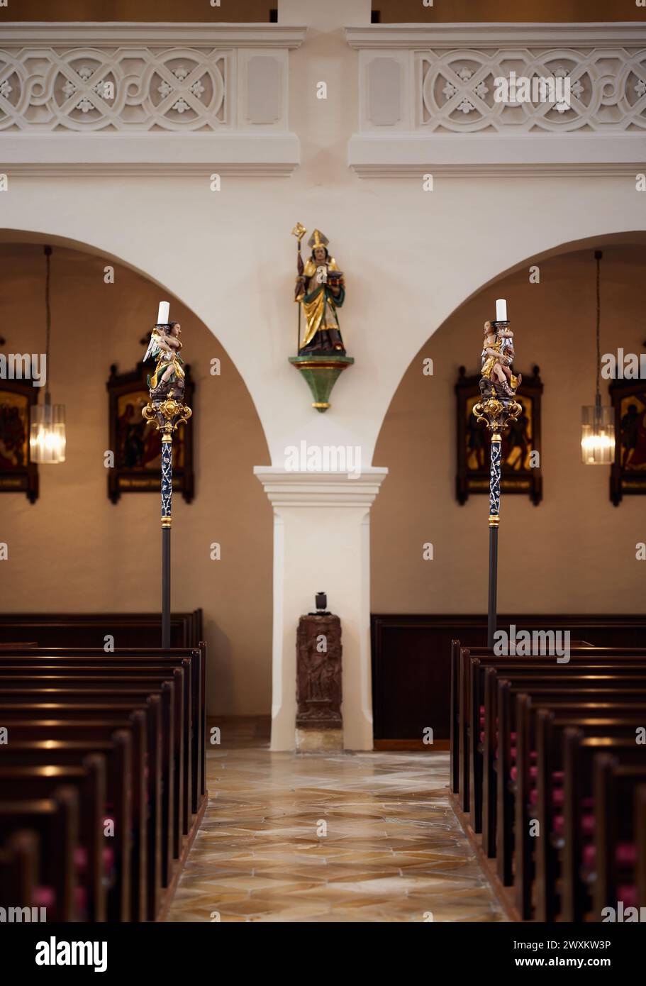 A church interior with statues and wooden pews on each side Stock Photo ...
