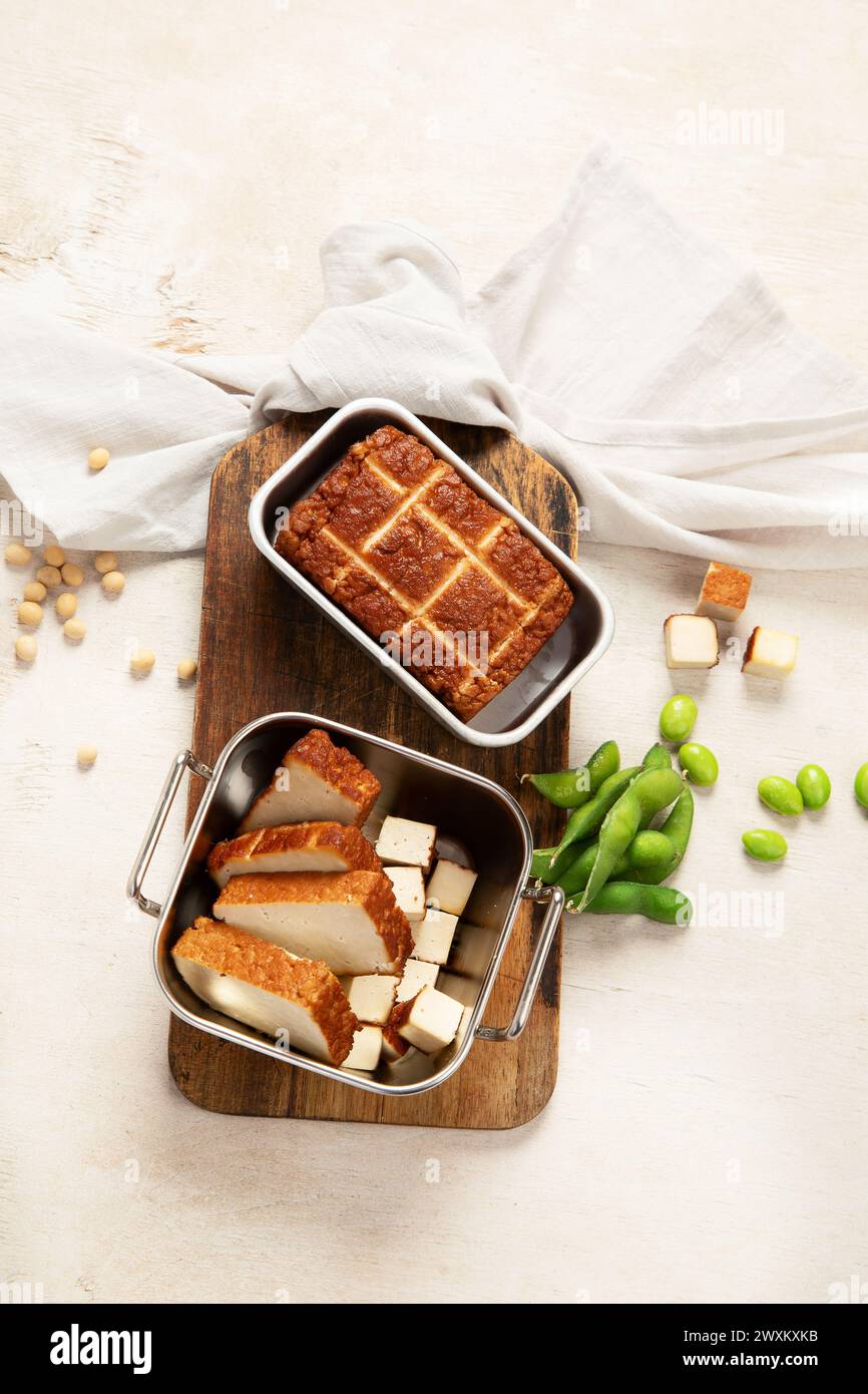 Soy food. Baked tofu cheese on a board, soybeans. Vegan product. Top ...